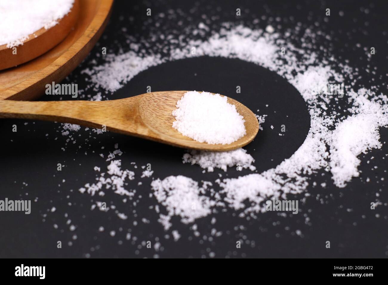 Wooden spoon has salt on it and surrounded by the circle shape of salt ...