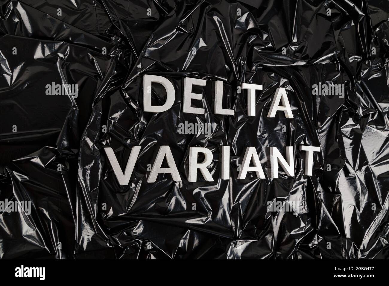 words delta variant laid with silver metal letters on crumpled black ...