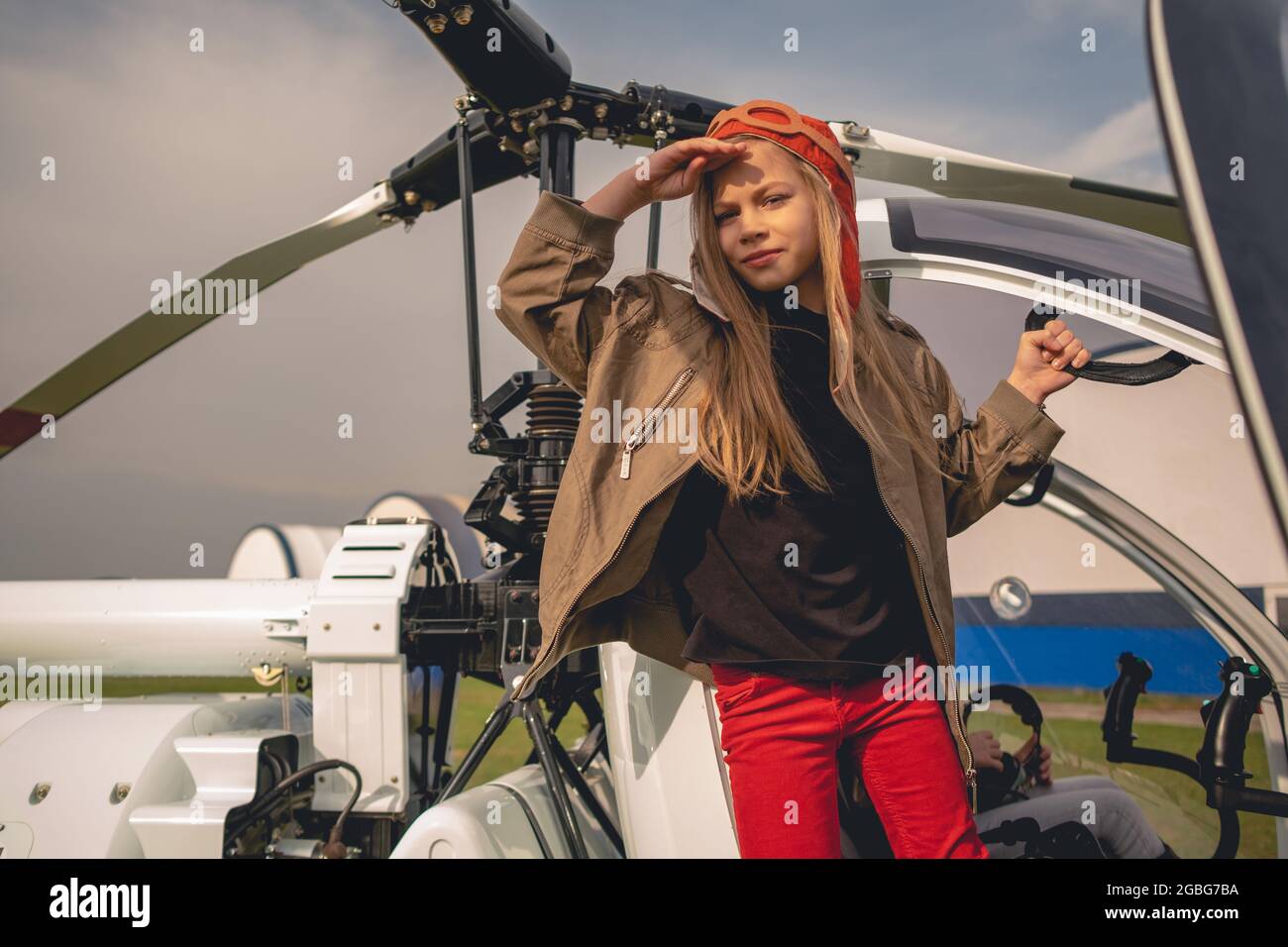 Serious preteen girl in aviator hat in doorway of open helicopter Stock ...