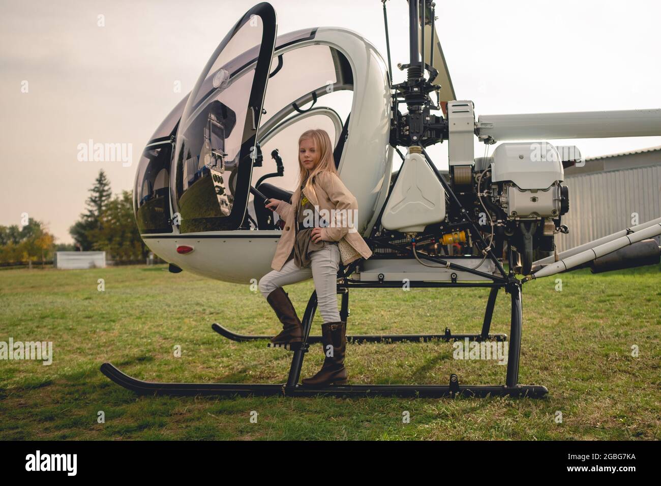 Full length portrait of blonde tween girl standing near helicopter ...