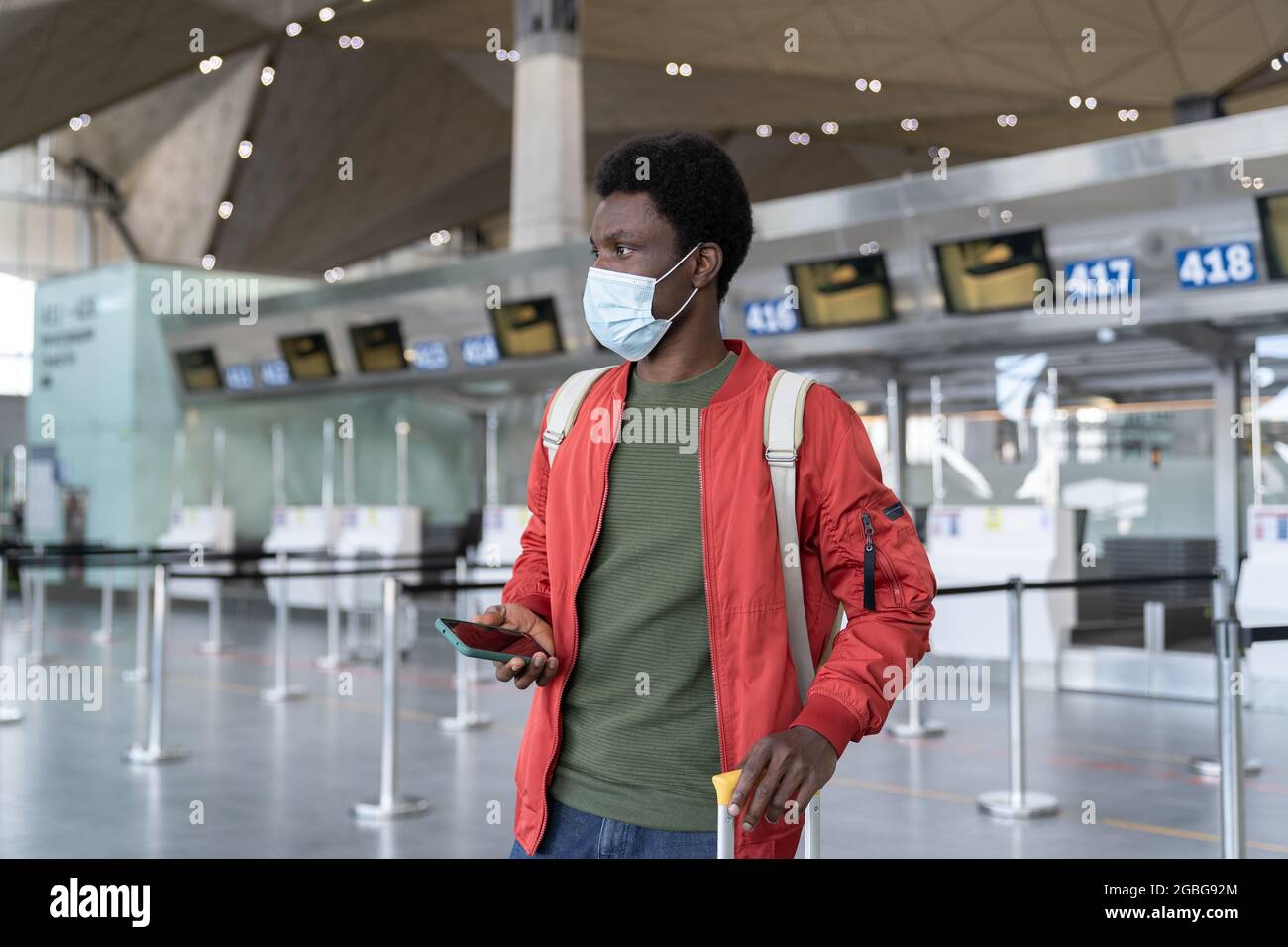 Young black male traveler in airport wait for flight use smartphone ...