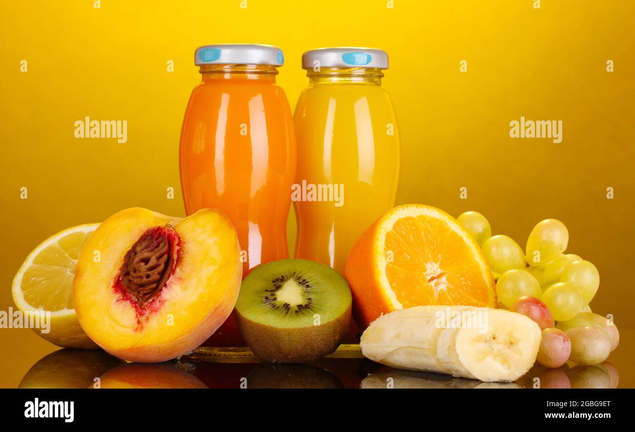 Delicious multifruit juice in a bottle and fruit next to it on yellow ...