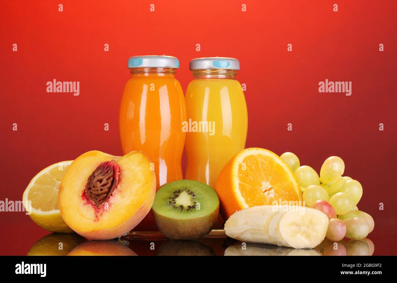 Delicious multifruit juice in a bottle and fruit next to it on red ...