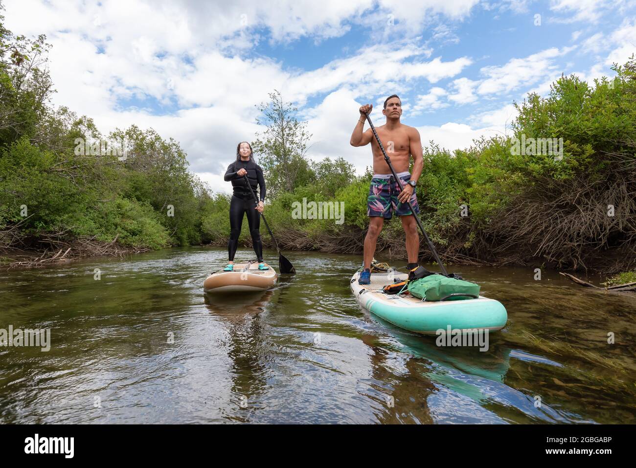 Adventurous people paddle boarding in a river Stock Photo - Alamy