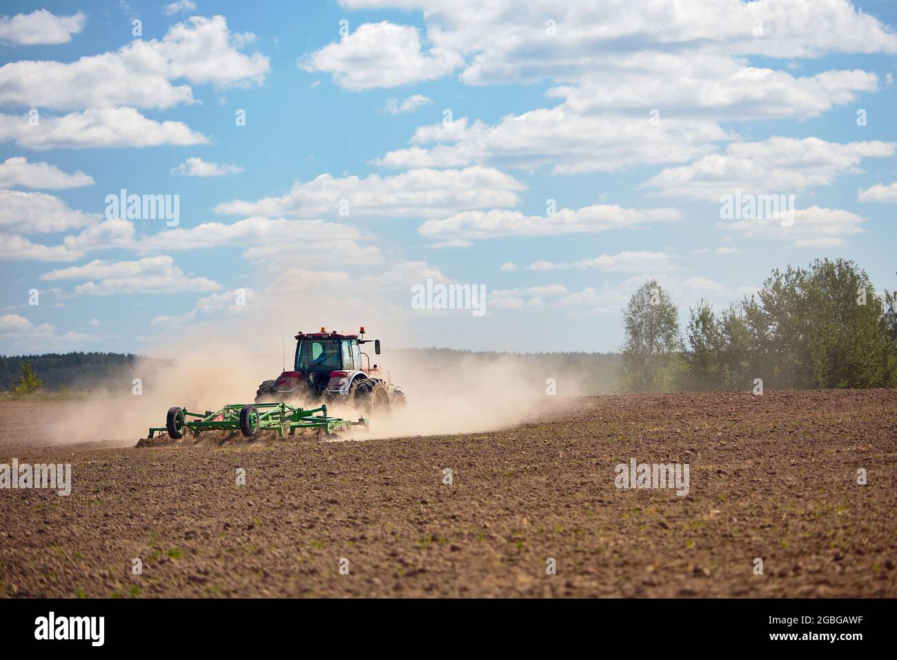 Typical agricultural scene tractor cultivation in field in clouds of ...