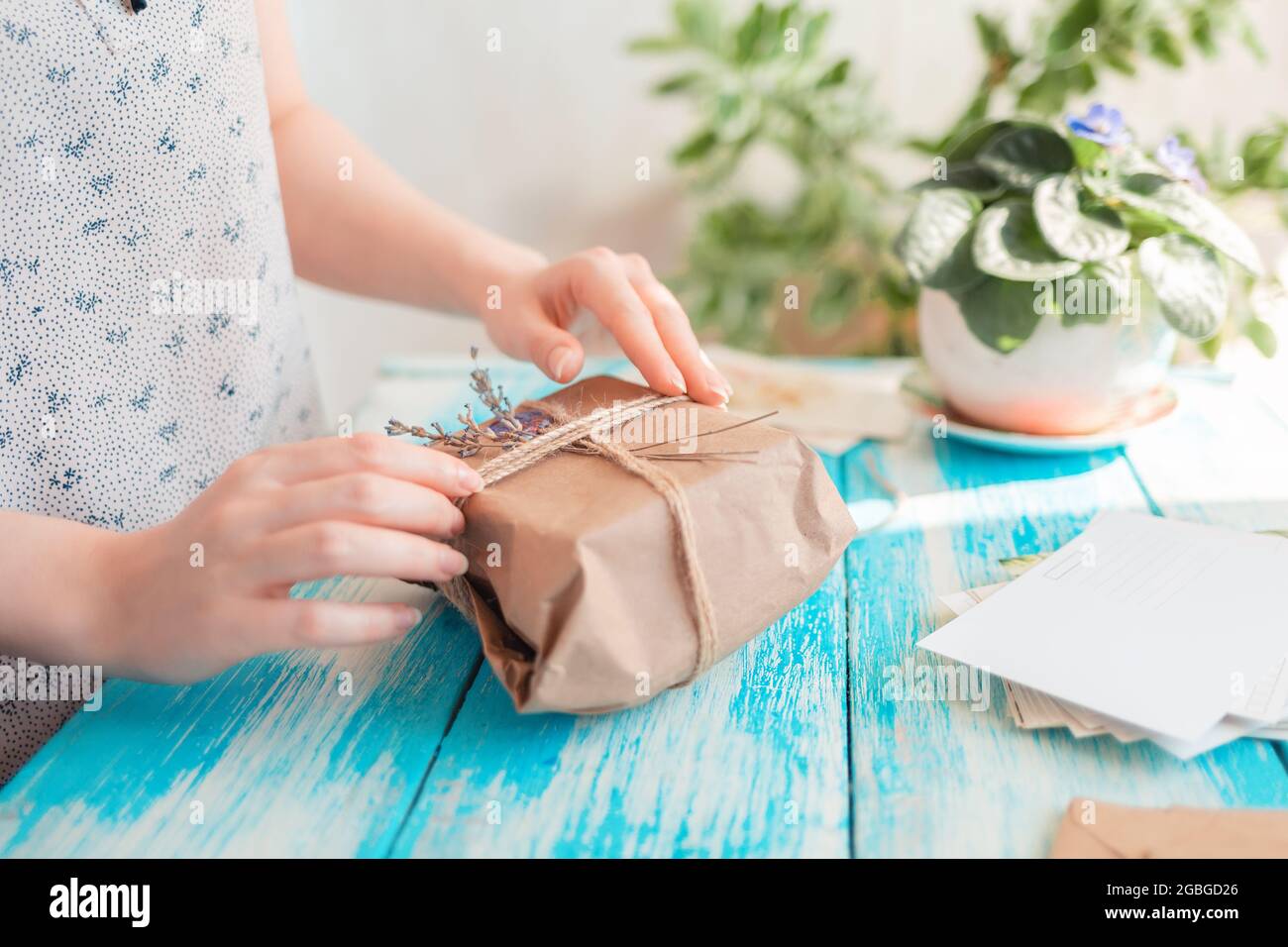 A female hands packs a parcel in craft paper wrapped with twine with ...