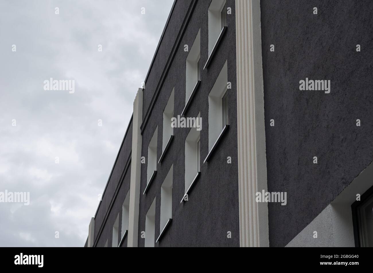 Dark-gray building with white windows against an overcast sky ...