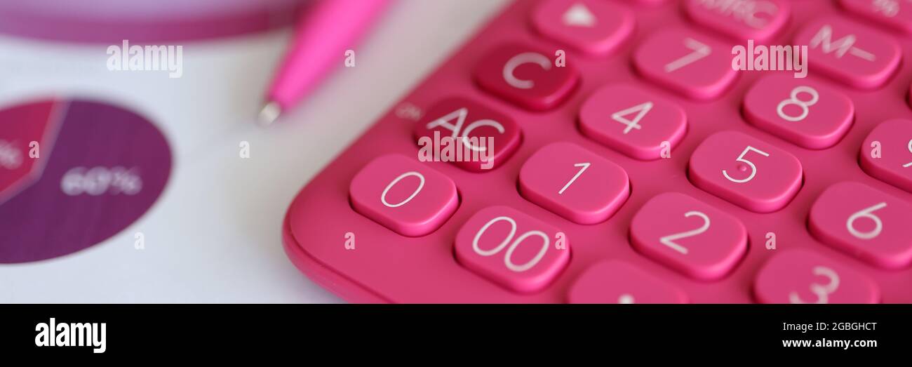 Pink calculator and pen lying on documents with graphs and diagrams ...