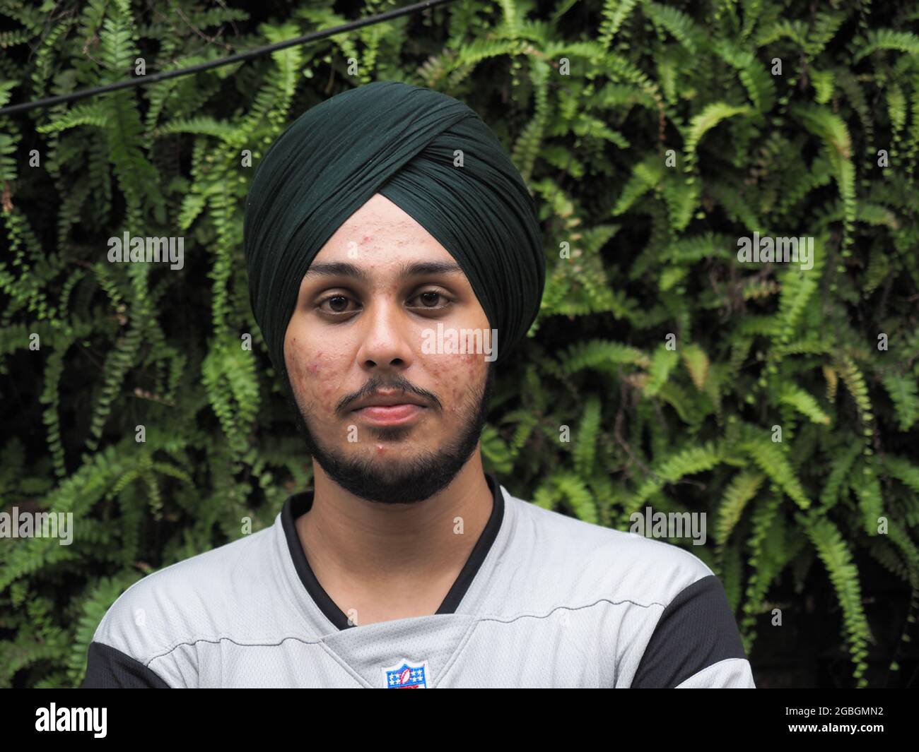 Indian Sikh teen boy wears an black patka in green outdoor background ...