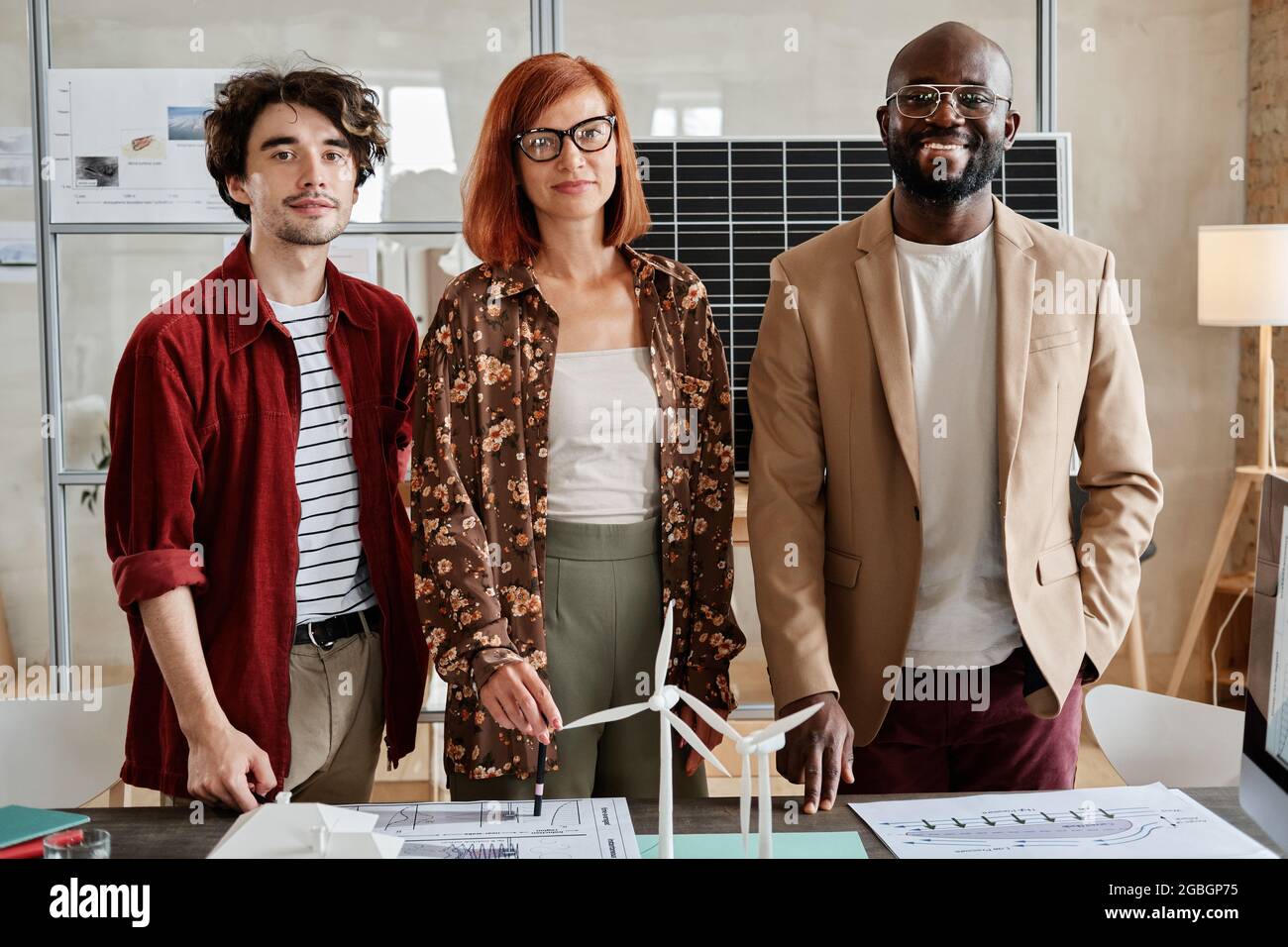 Portrait of successful group of architects smiling at camera while ...