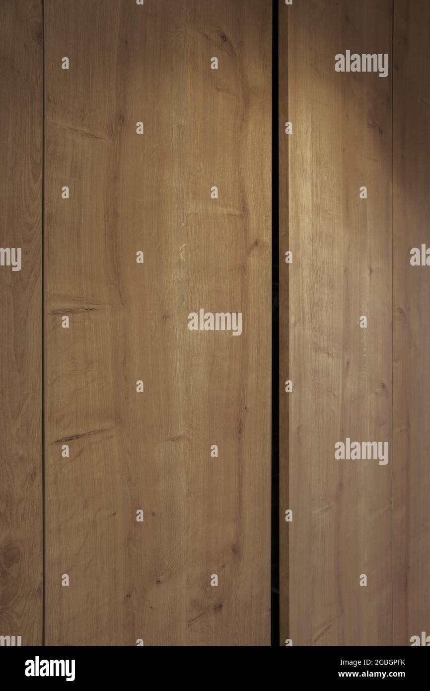 Vertical shot of closed wooden closet doors with a black line in the ...
