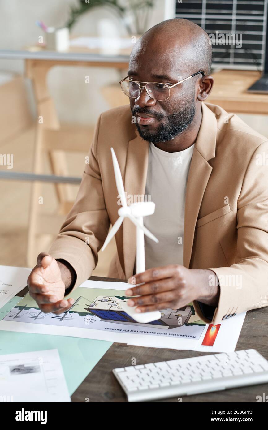 African engineer sitting at the table with blueprint and presenting new ...