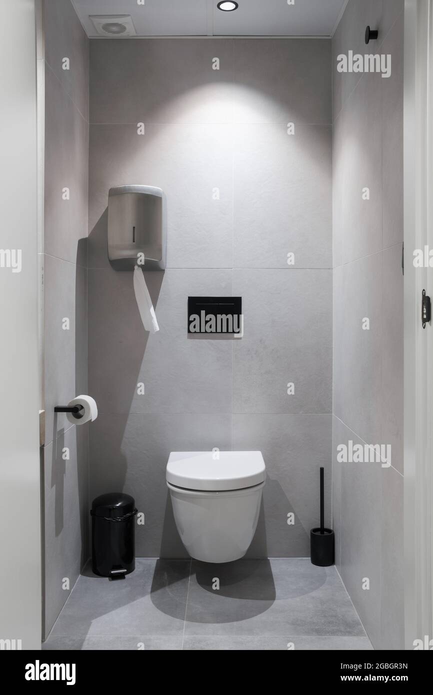 Vertical shot of a clear toilet room with gray tiled walls and toilet ...