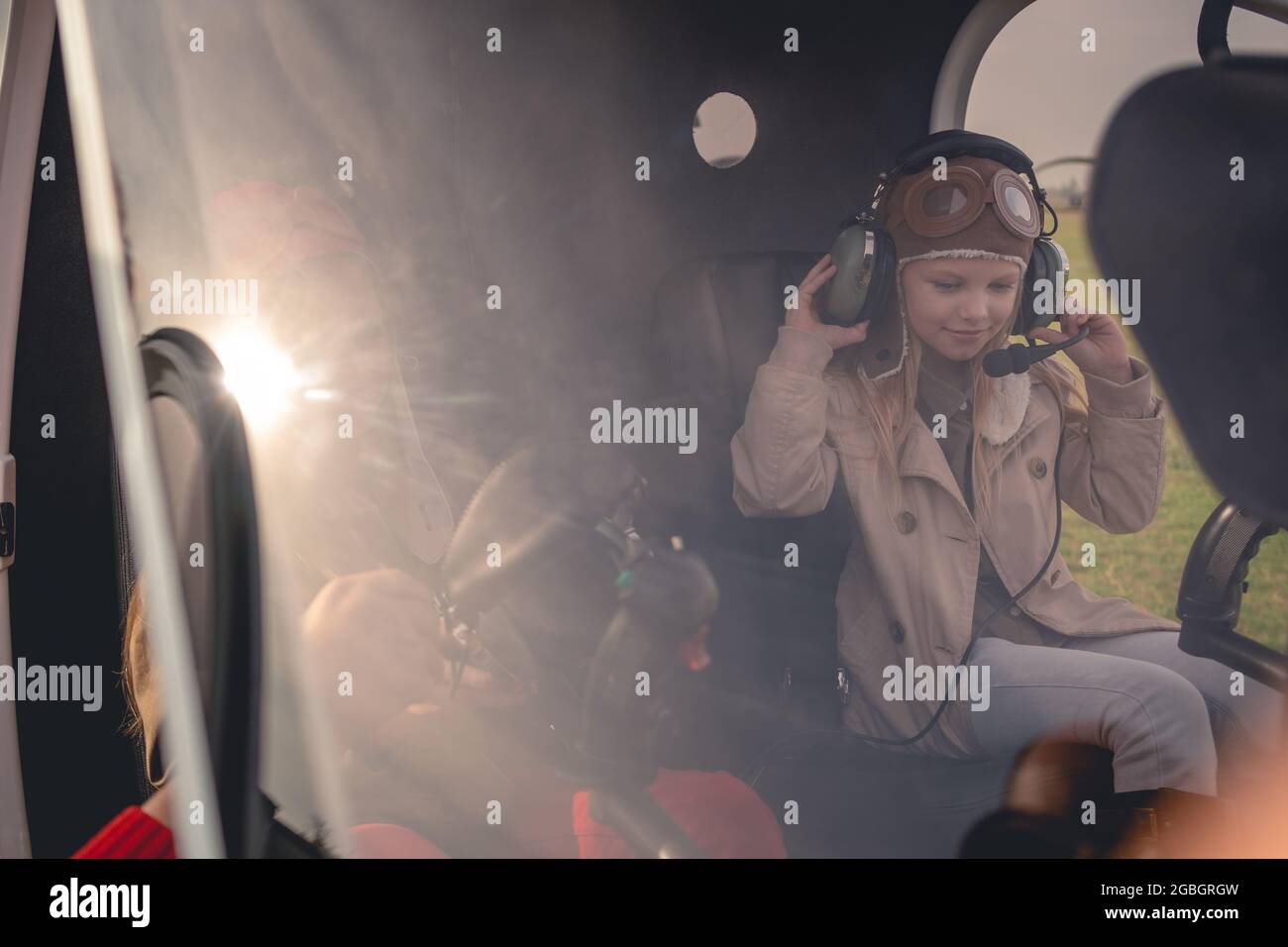 Tween girl putting on headset on pilot seat in helicopter Stock Photo ...