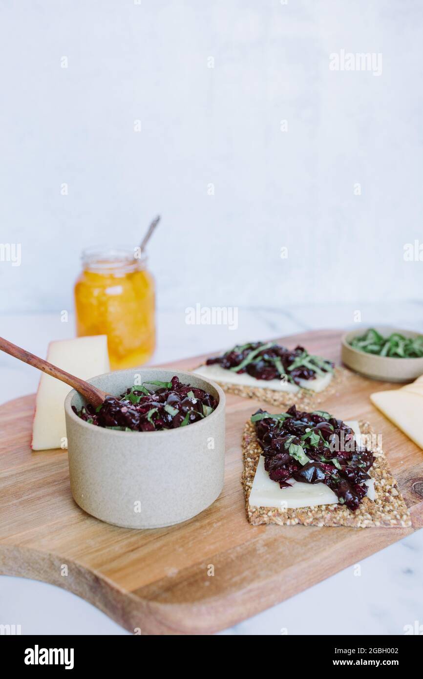 Vertical closeup of cherry relish, basil garnish, and manchego cheese ...