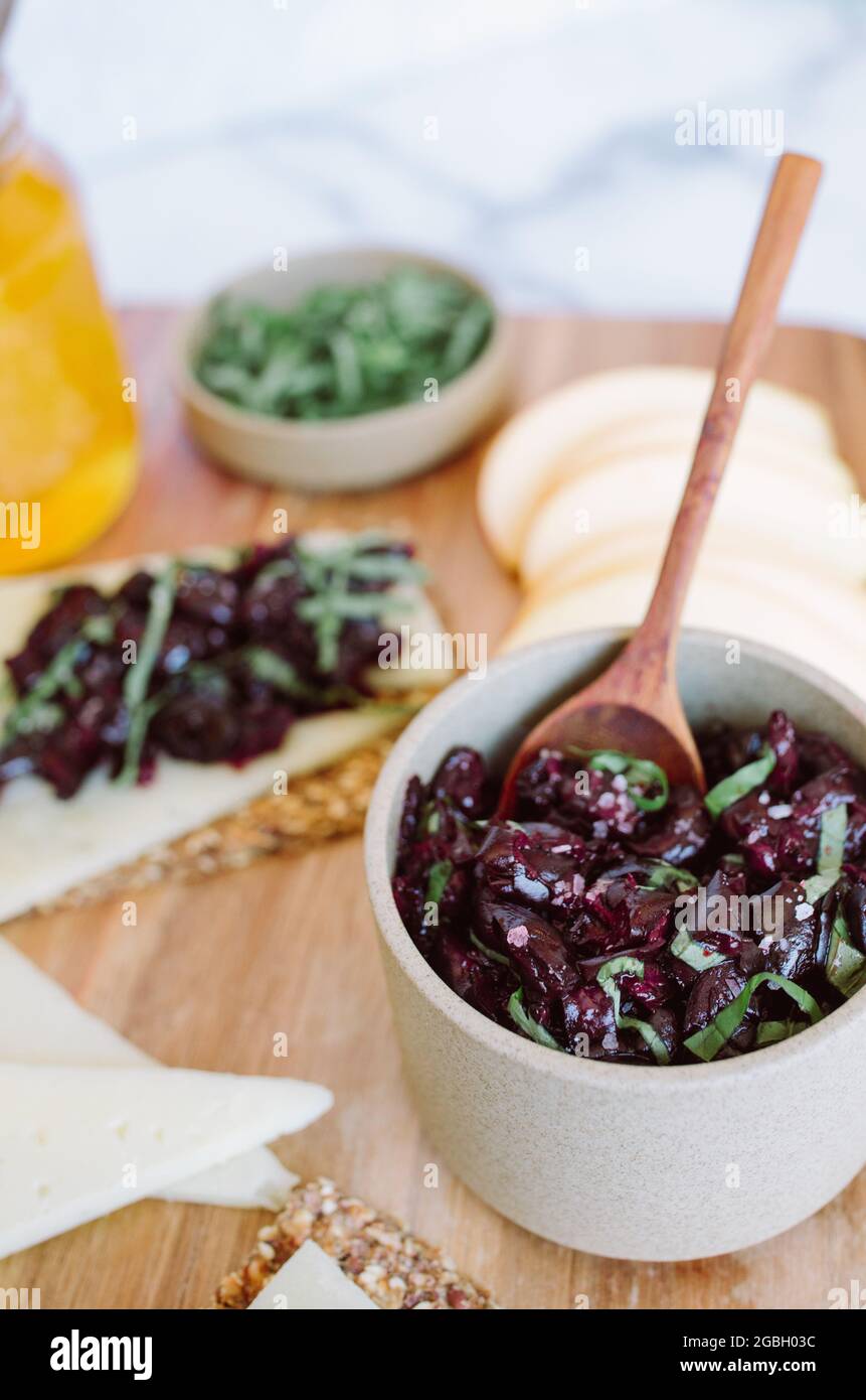 Vertical shot of cherry relish with basil garnish in a clay bowl ...