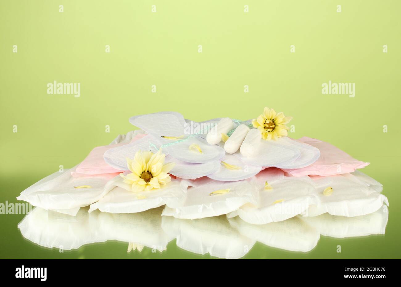 various types of sanitary pads and tampons on green background close-up ...