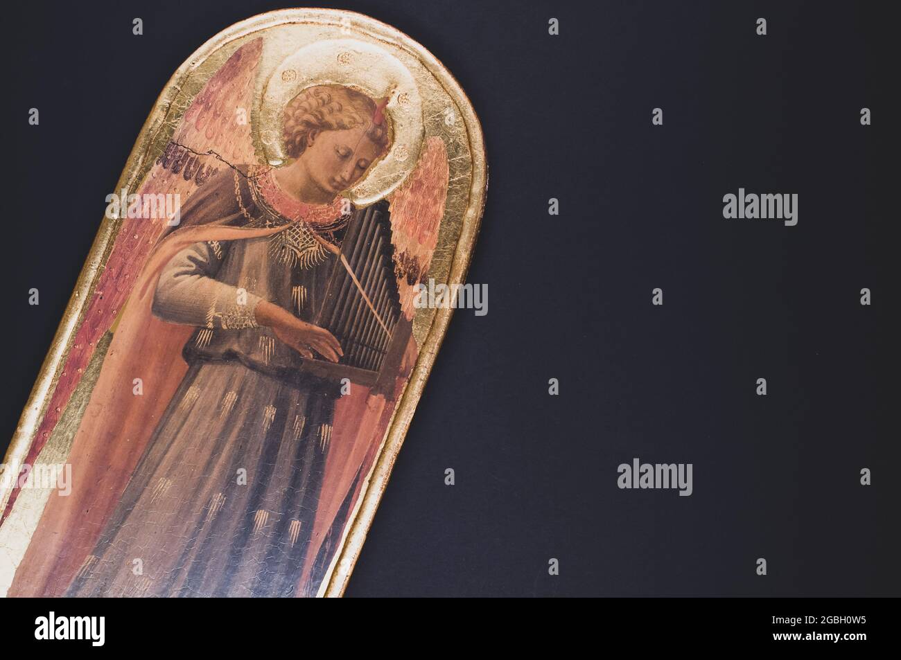 Angel ornament playing a string instrument on a black background with ...