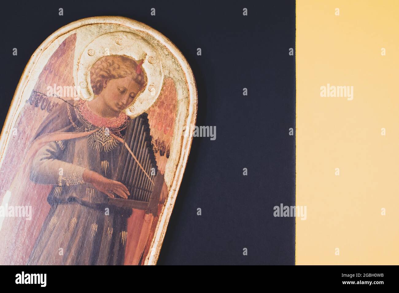 Angel ornament playing a string instrument on a black and yellow ...