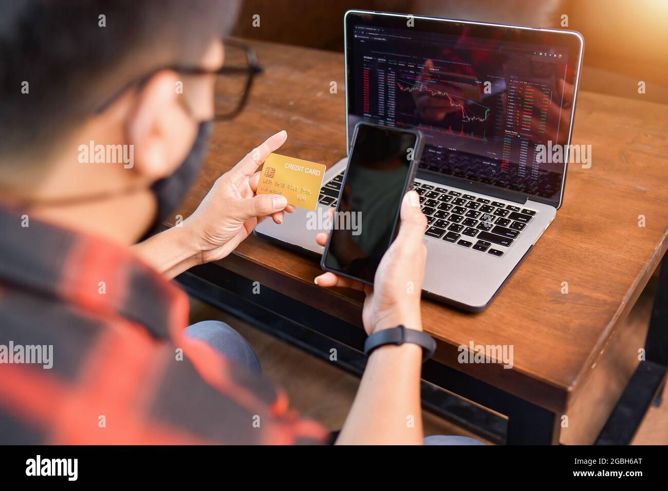Man sitting in front of a laptop with his credit card making a mobile ...