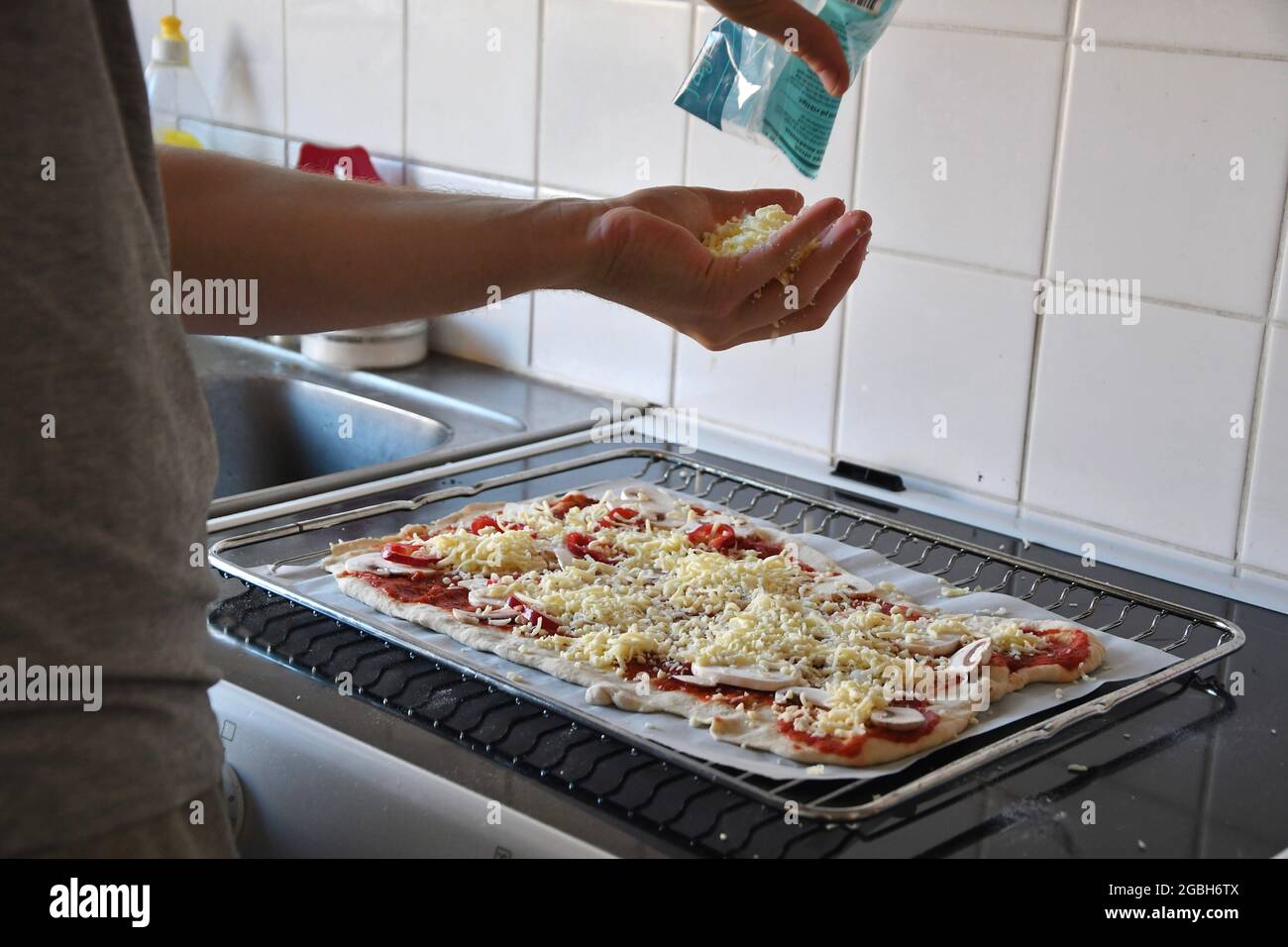 A man putting cheese on pizza, cooking food in the kitchen Stock Photo ...