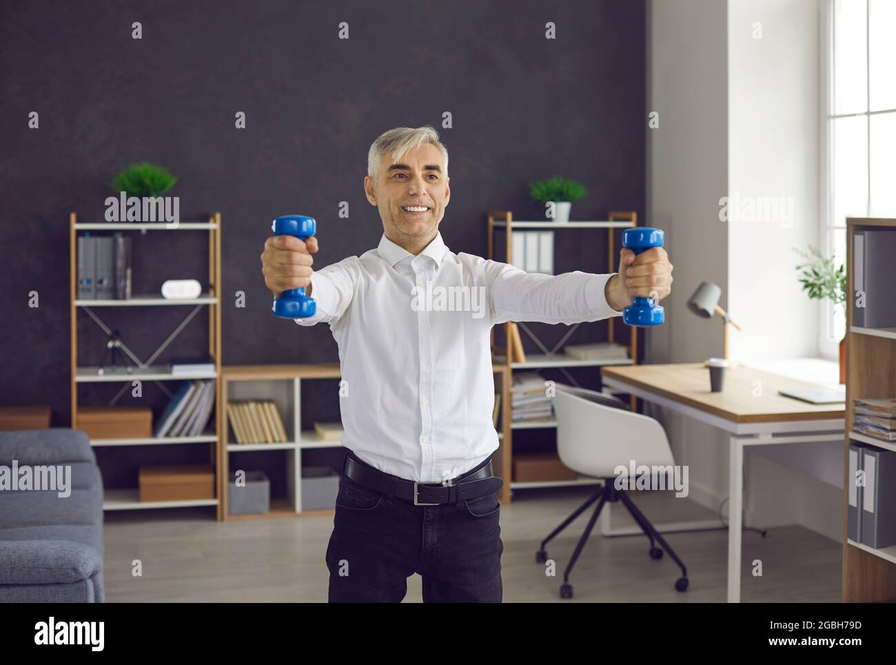 Happy senior man doing sports exercise during his working day in office ...