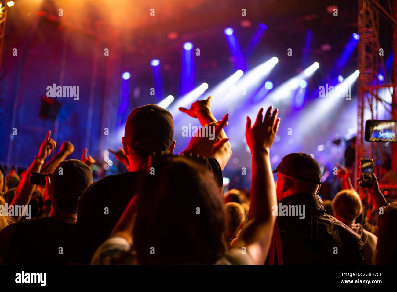 group of fans raised their hands up at a music concert, dancing ...