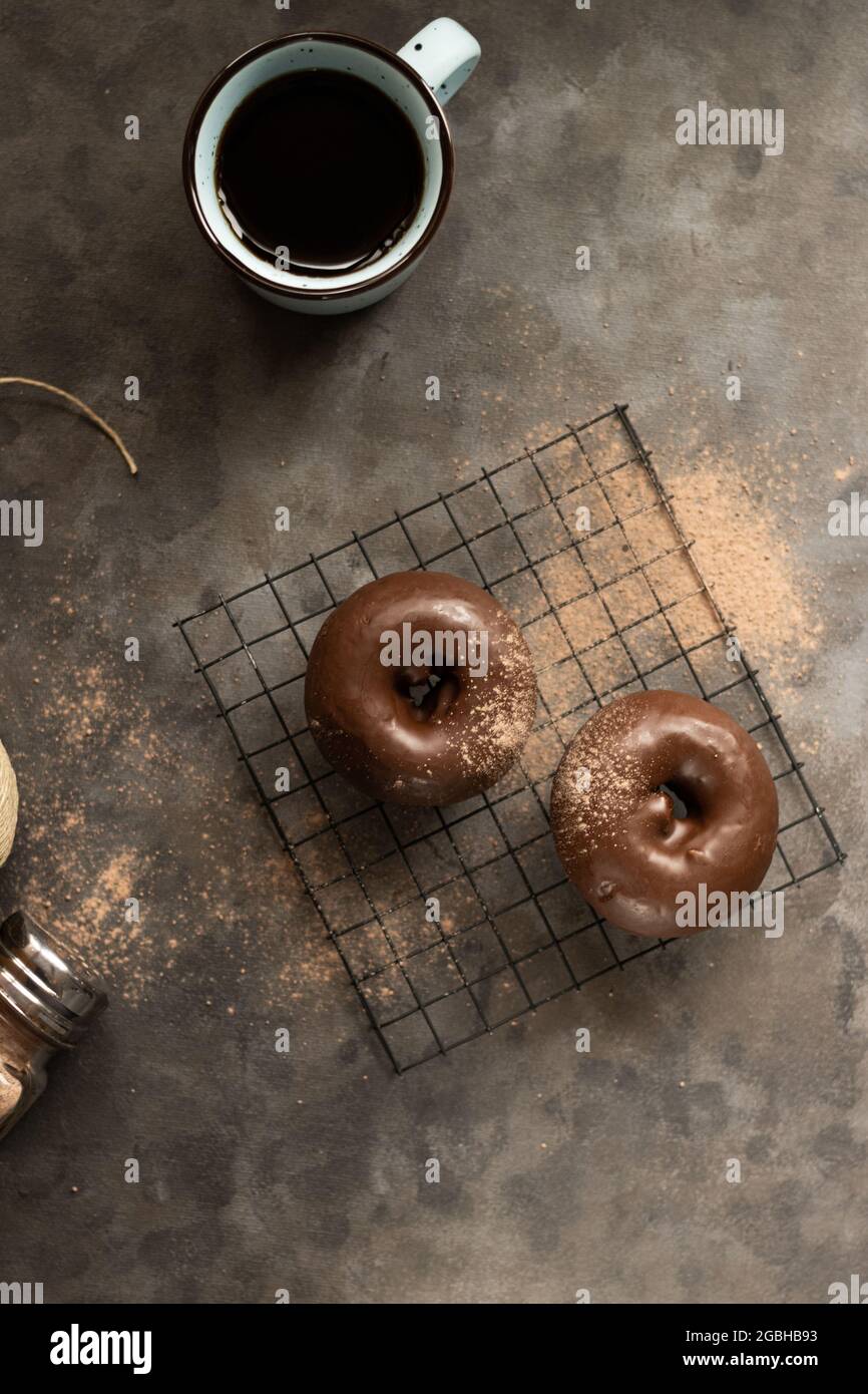 Vertical top view of a cup of coffee and chocolate donuts on a kitchen ...