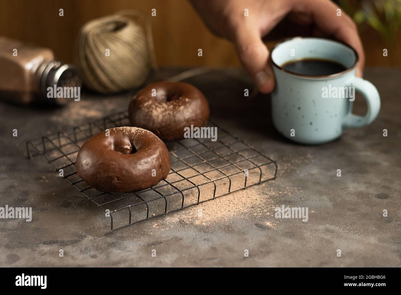 Hand picking up a cup of coffee from a table with chocolate donuts ...