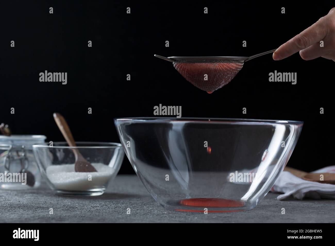 Woman straining strawberry jam through a sieve, home cooking and ...