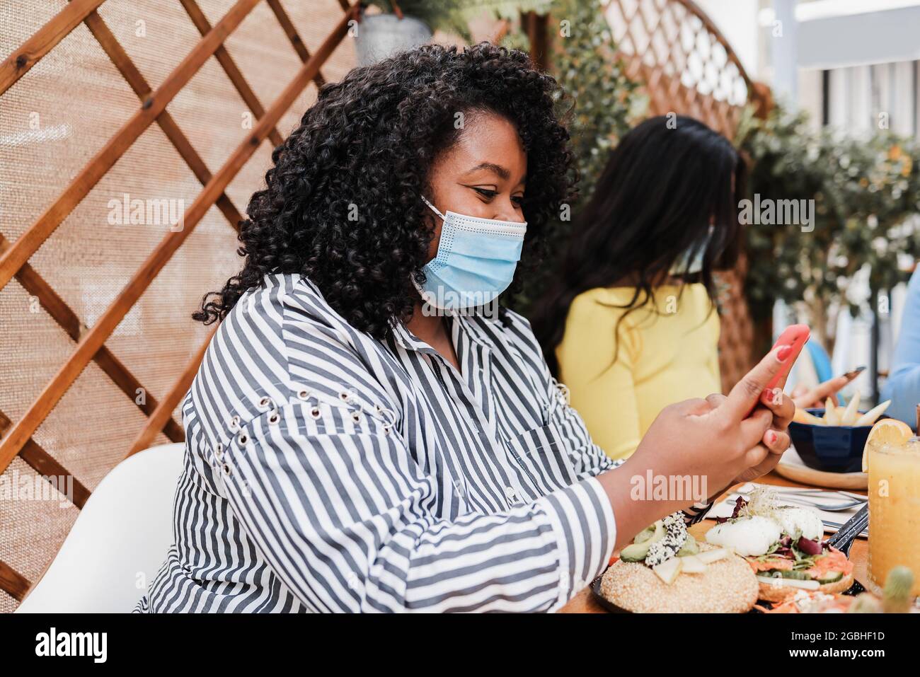 Happy Multiracial Friends Using Mobile Phones Outdoors At Brunch