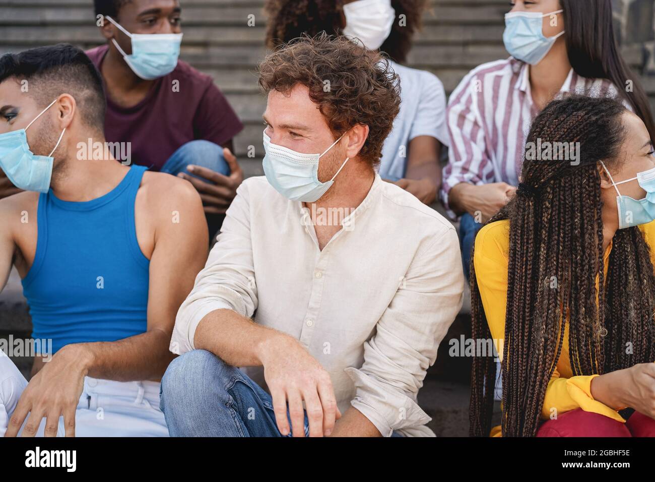 Young diverse people laughing together wearing safety mask outdoor in ...