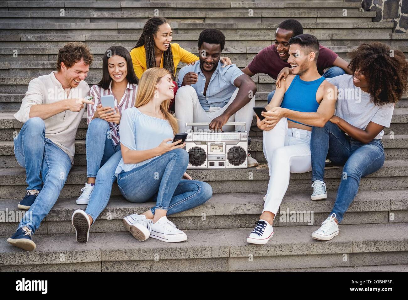 Young diverse people having fun listening music with boombox stereo ...