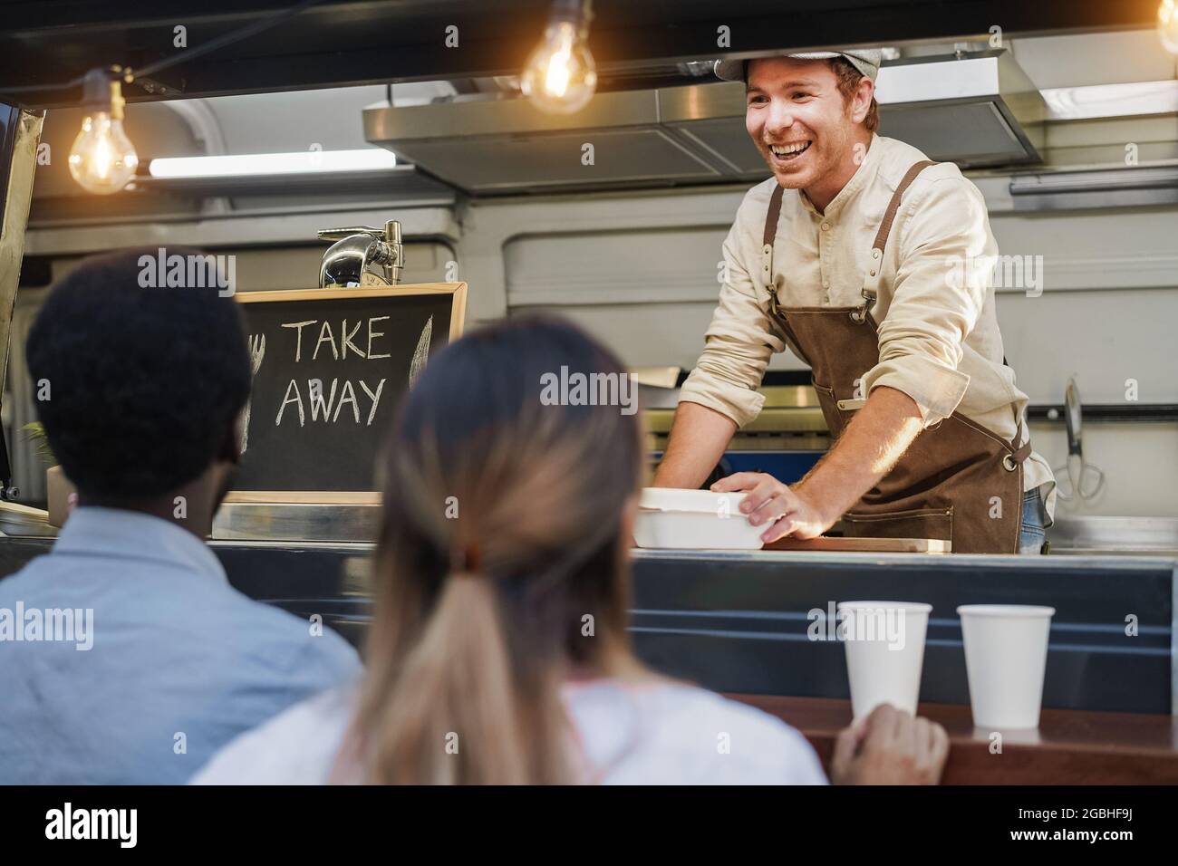 Hispanic man serving take away food inside food truck - Focus on chef ...