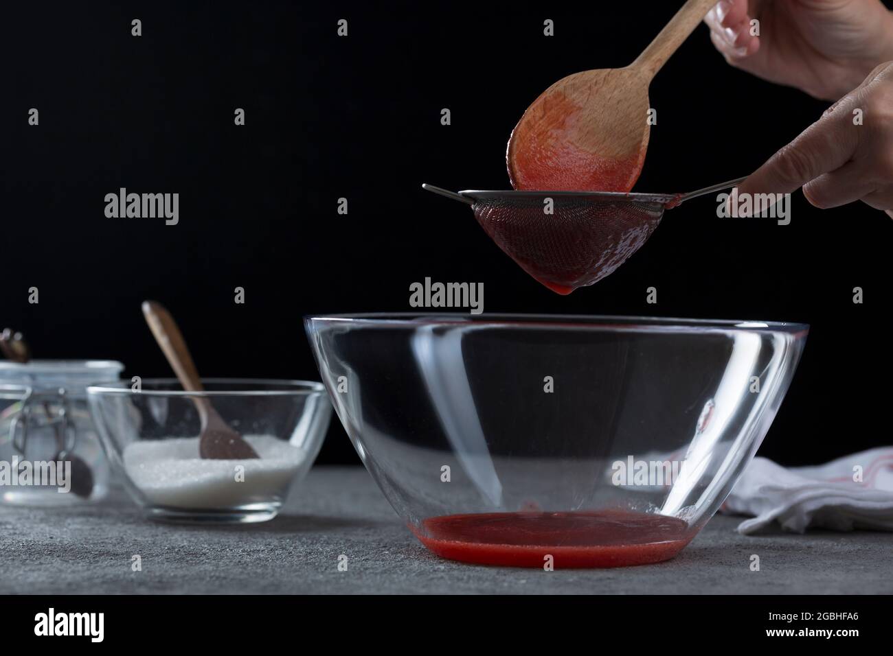 Woman straining strawberry jam through a sieve, home cooking and ...