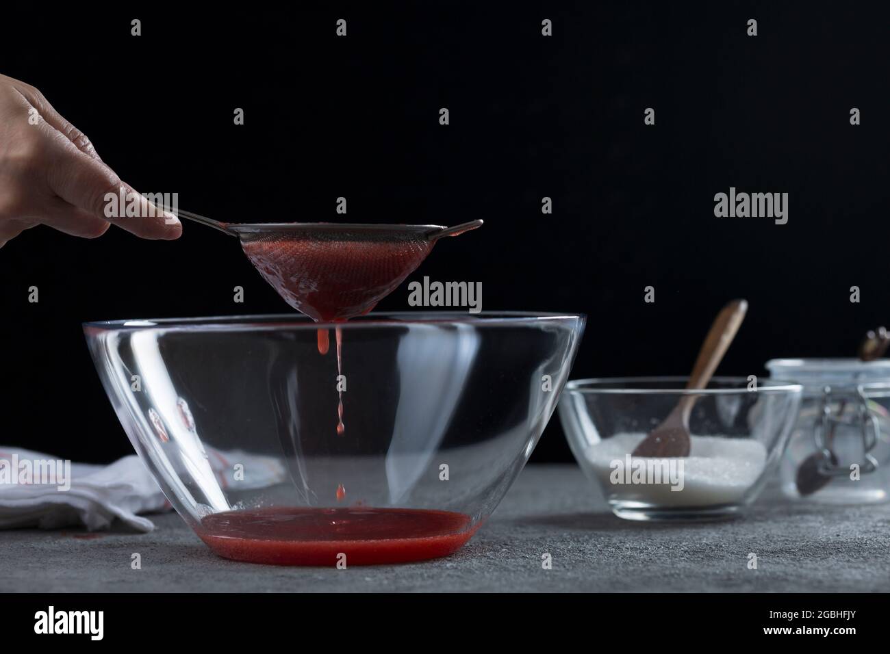 Woman straining strawberry jam through a sieve, home cooking and ...