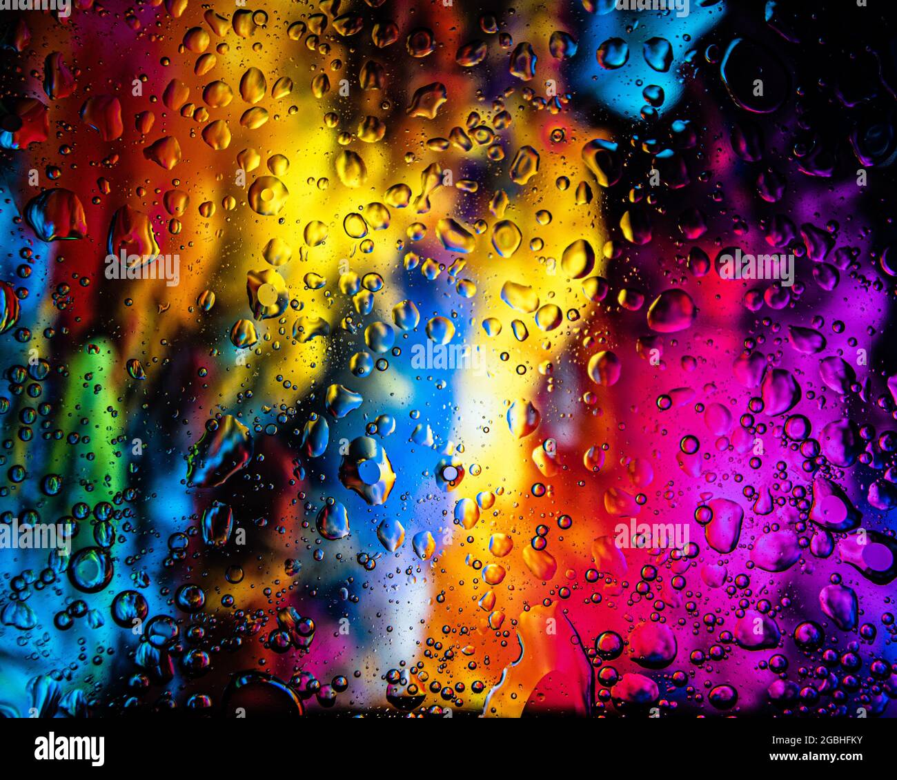 Vertical shot of waterdrops on a glass surface with colorful textures ...