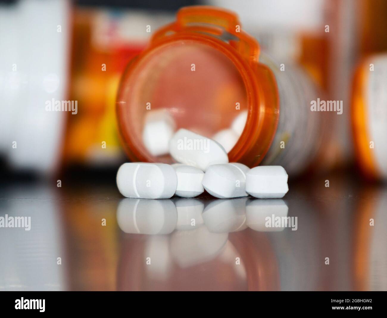 White drugs spilling out of a prescription pill bottle lying on its ...