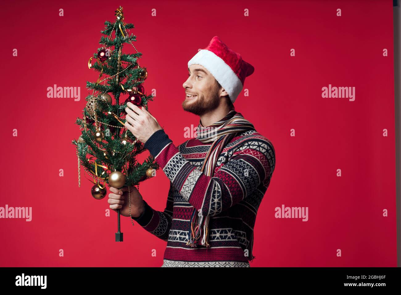 a man in a Santa hat Christmas tree decoration toys red background ...
