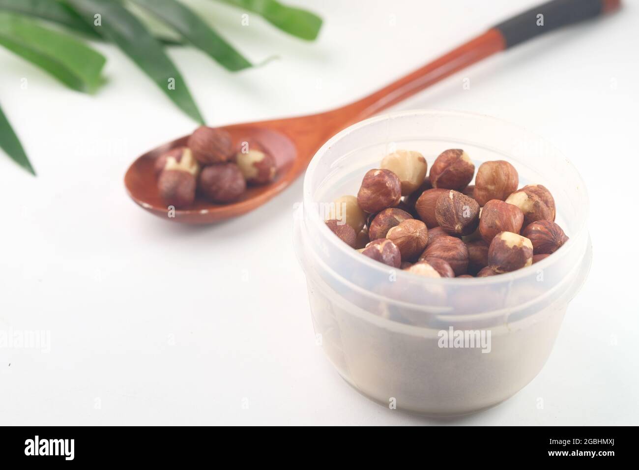 hazelnuts in a container on white background Stock Photo - Alamy