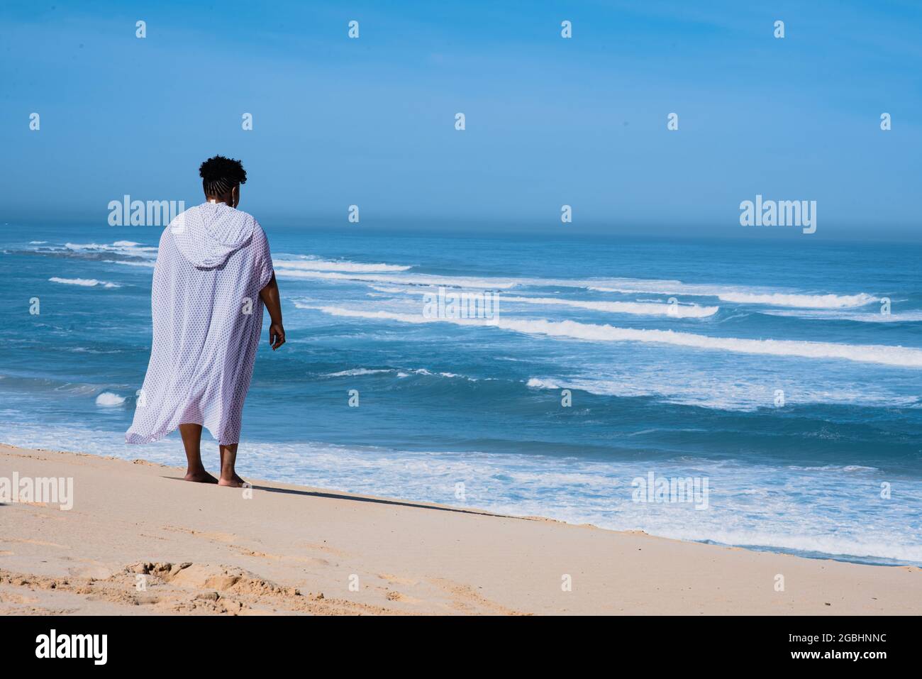 Woman seen standing on sand and watching the ocean Stock Photo - Alamy