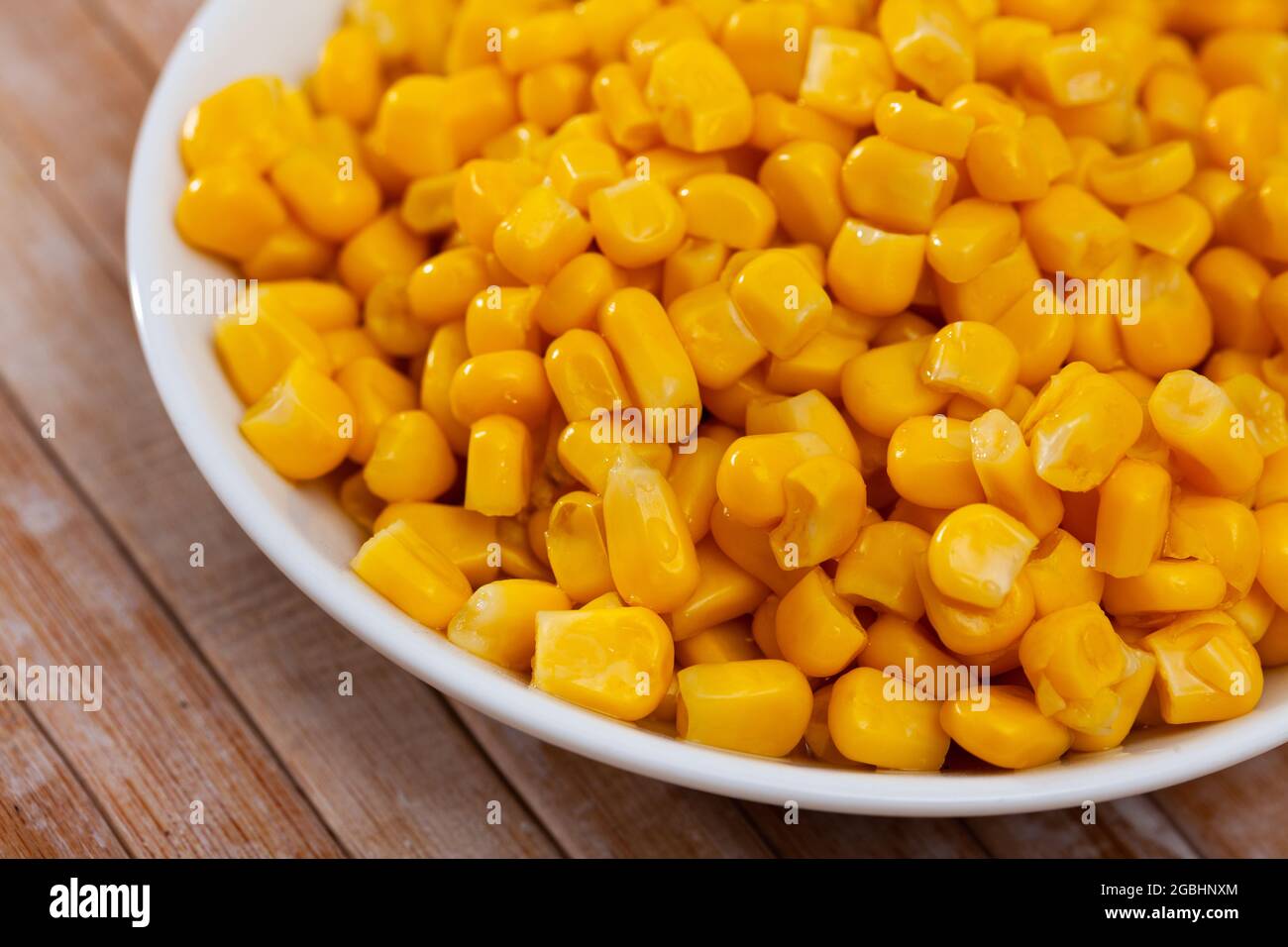 Plate with grains of boiled corn on wooden table Stock Photo - Alamy