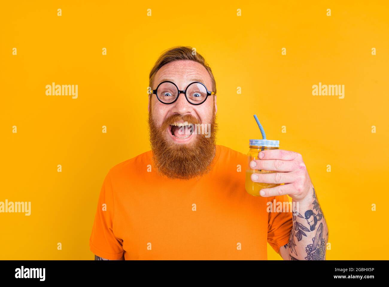 Nerd happy man with glasses drinks a fruit juice Stock Photo - Alamy