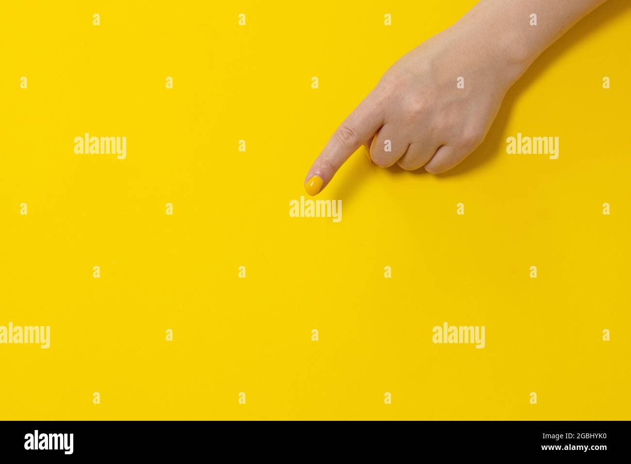 Hand finger pointing at something on yellow background, closeup. Hand ...