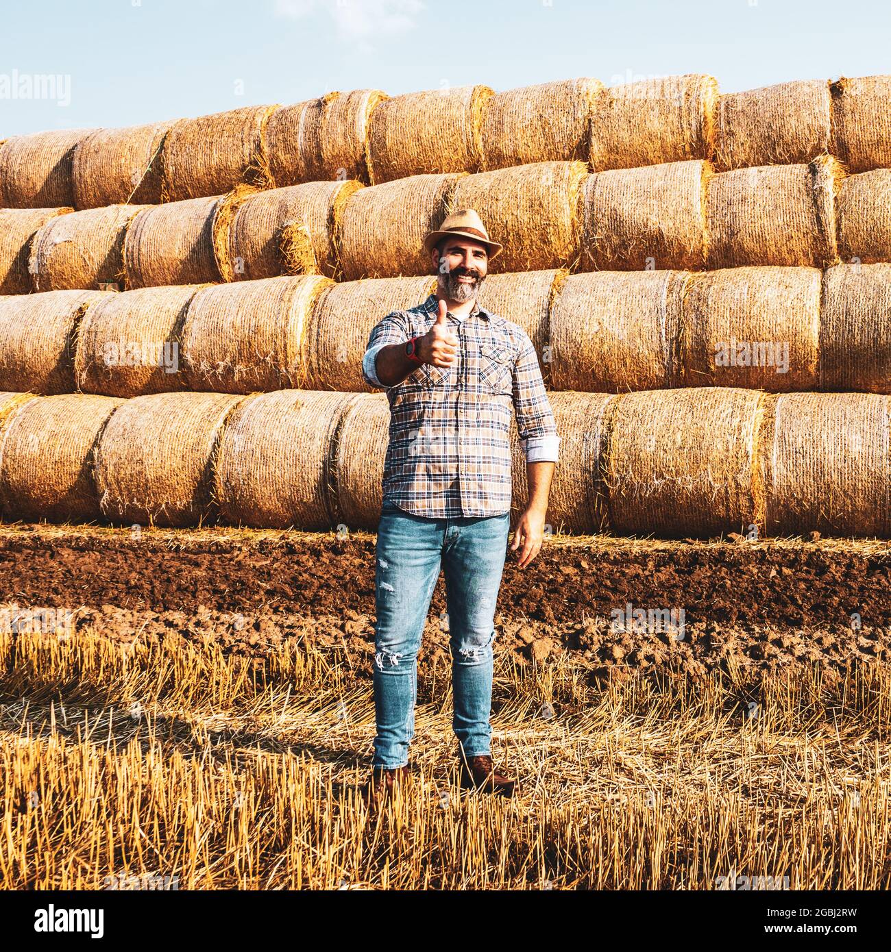Happy farmer is standing beside bales of hay. He is satisfied because ...
