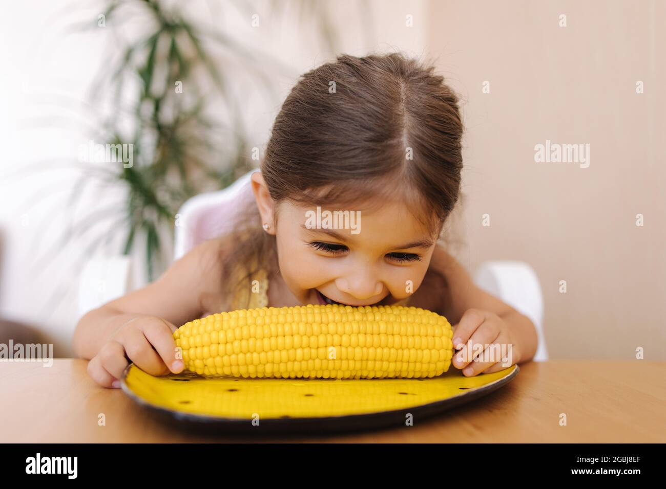 Adorable little girl eating corn at home. Cute kid tree year old eat ...