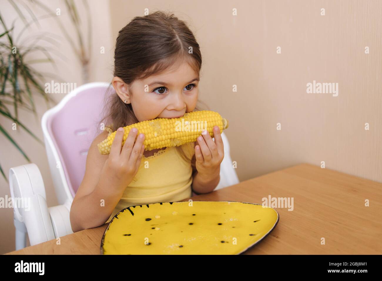 Adorable little girl eating corn at home. Cute kid tree year old eat ...