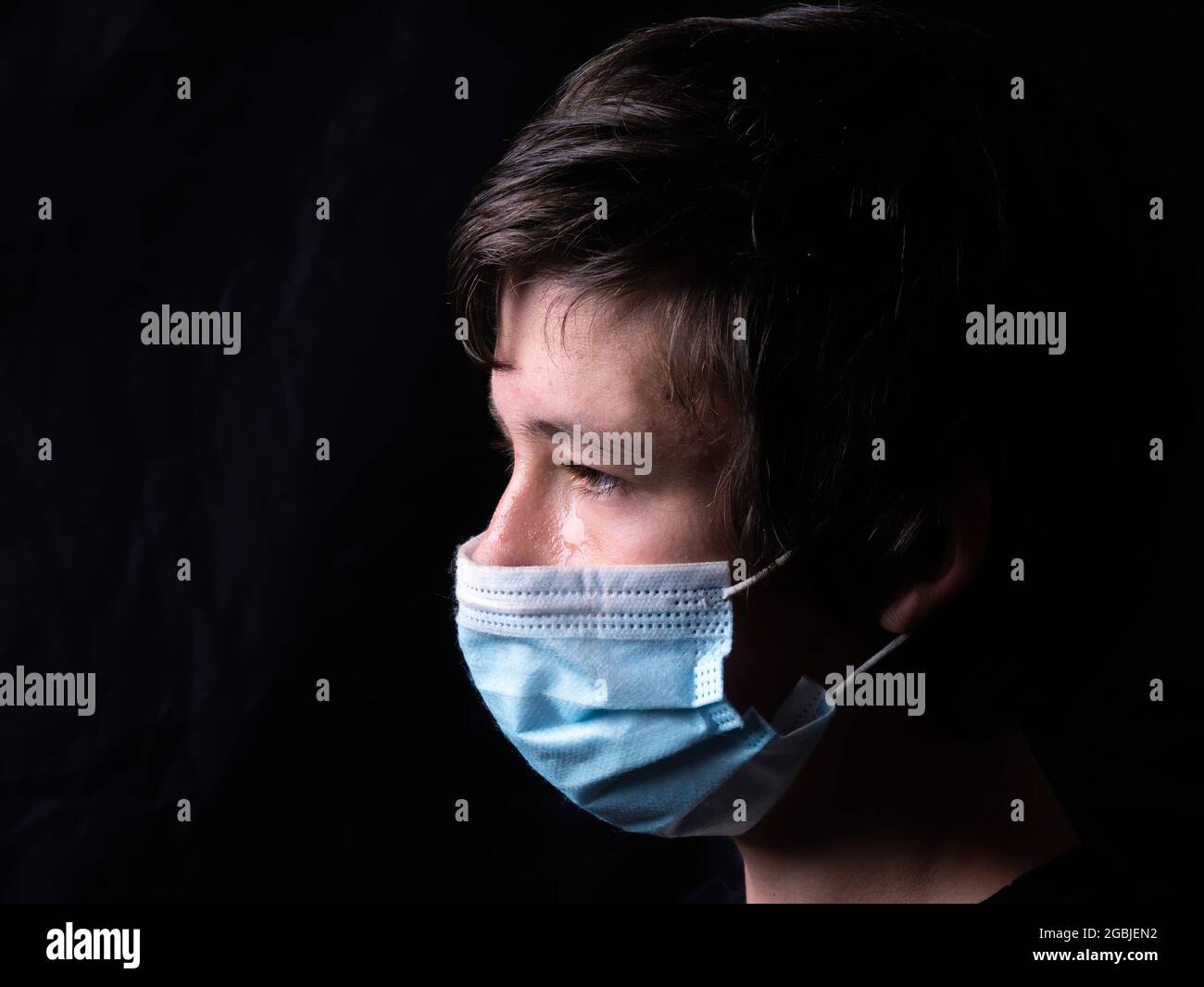 Crying Teenager With Medical Face Mask And Tears In Eyes Against Dark ...