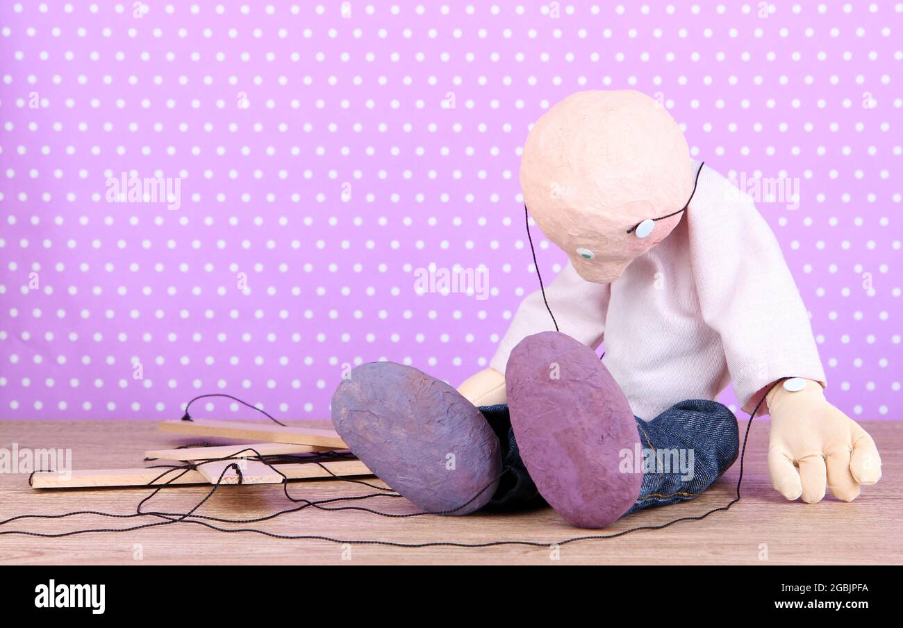Wooden puppet sitting on polka dot background Stock Photo - Alamy