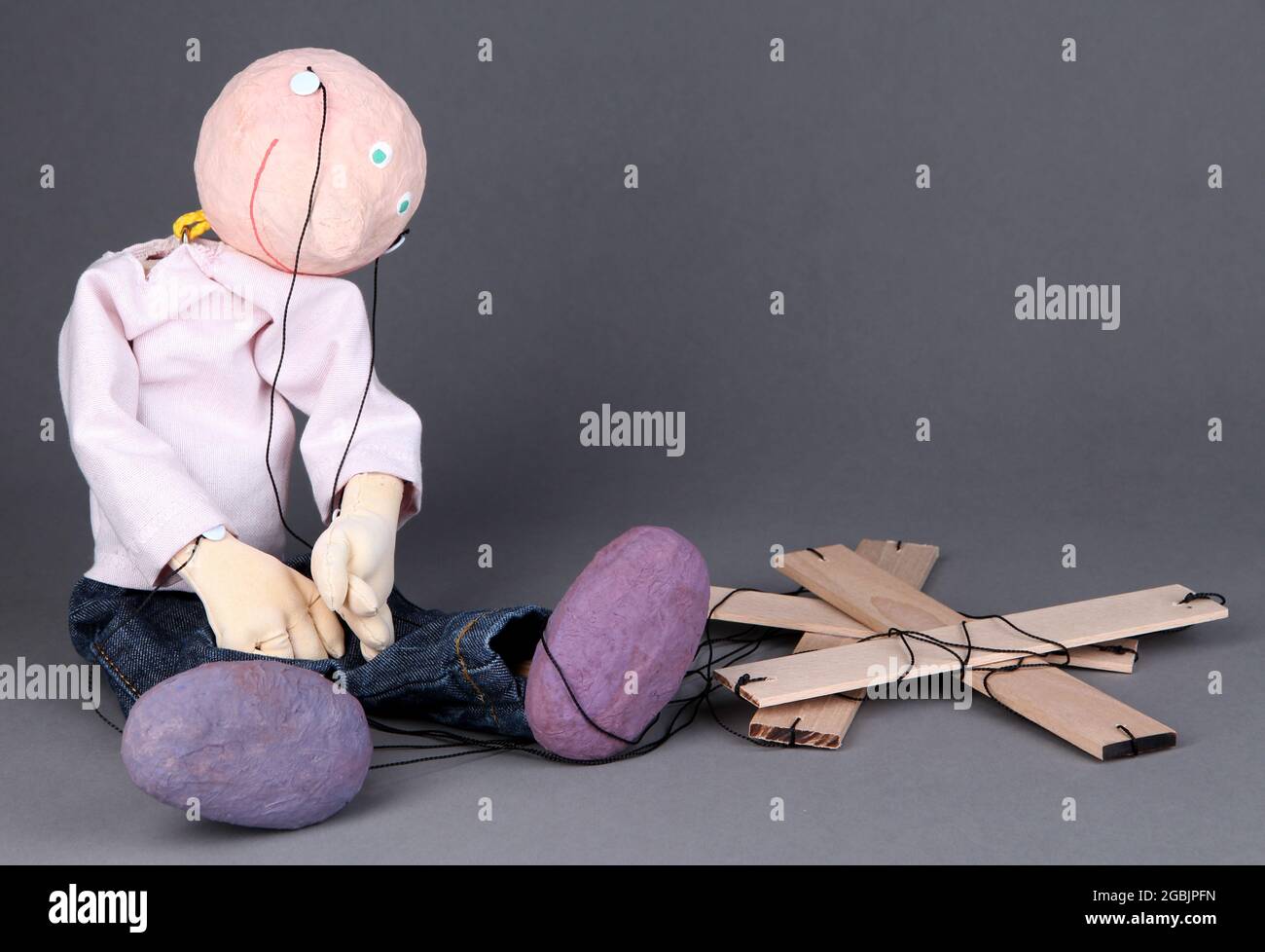 Wooden puppet sitting on grey background Stock Photo - Alamy
